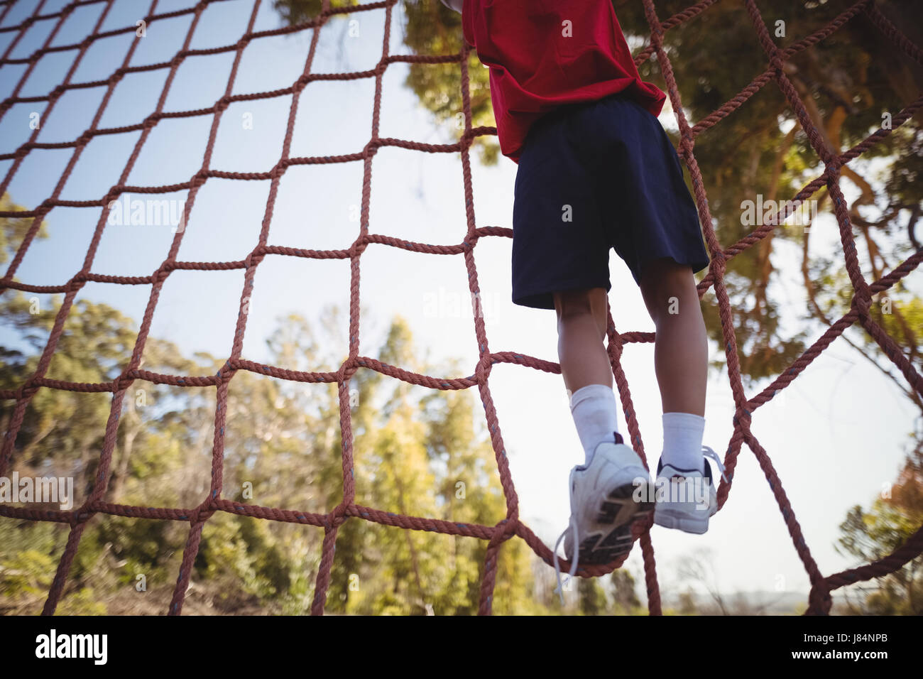 Boy climbing a net during obstacle course in camp Stock Photo - Alamy