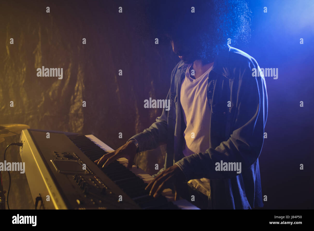Serious male musician playing piano in illuminated nightclub Stock ...