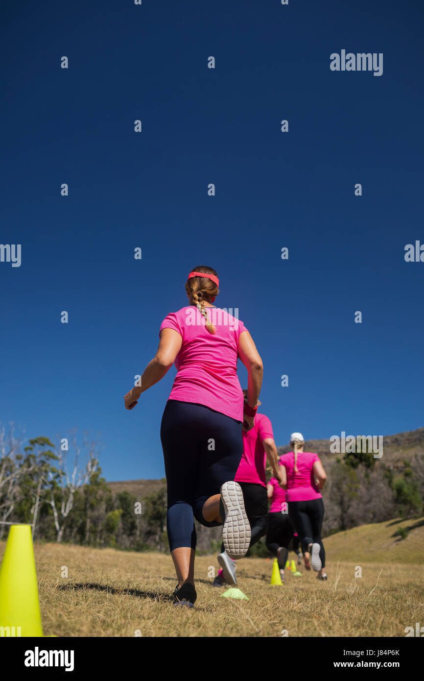 Group of women running through cones in the boot camp on a sunny day ...