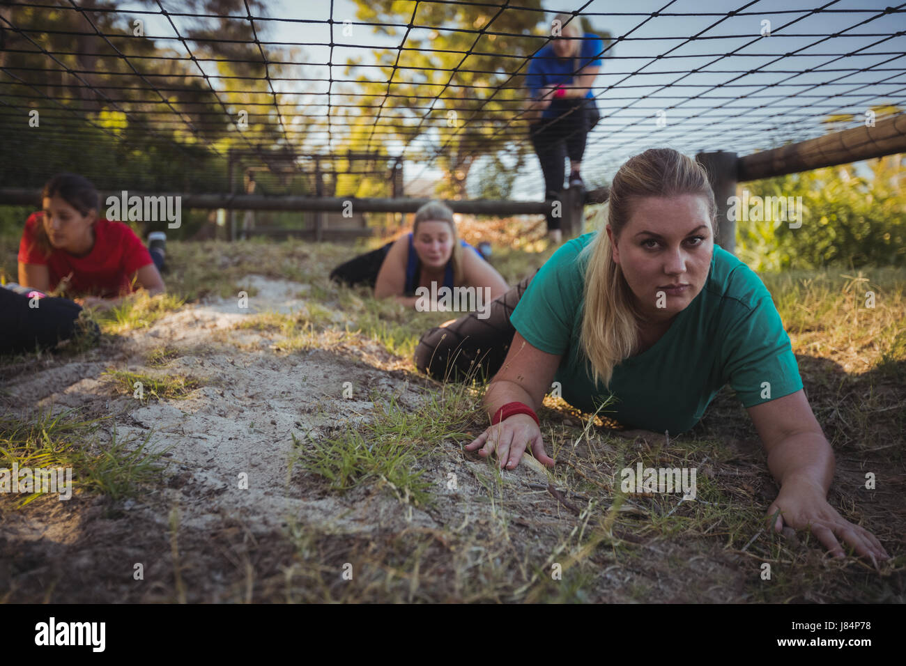 Group of fit women crawling under the net during obstacle course ...