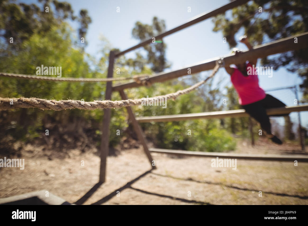 Woman exercising on outdoor equipment during obstacle course in boot ...