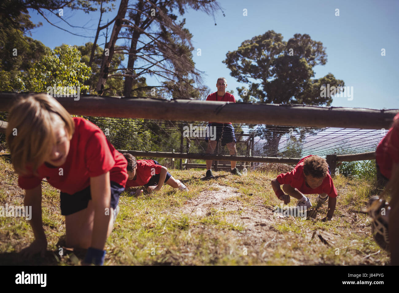 Kids crawling under the net during obstacle course training in the boot ...