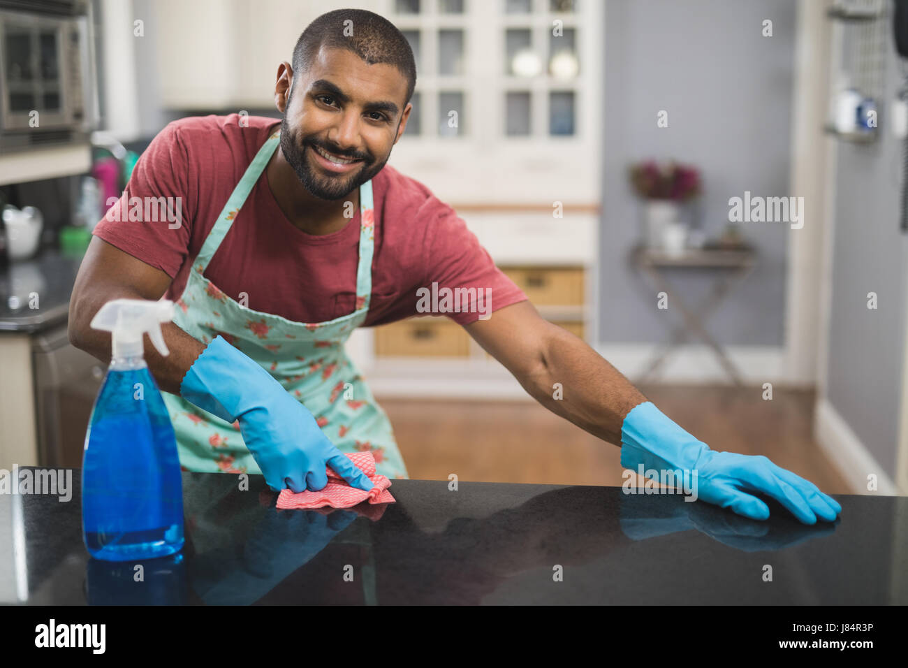 Portrait of smiling young man cleaning counter in kitchen at home Stock ...