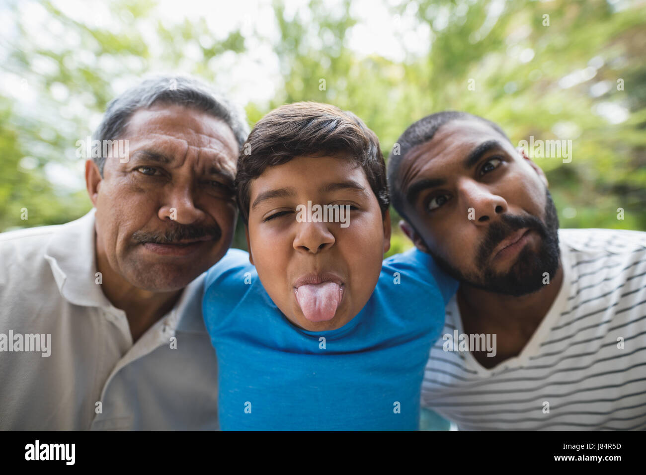 Portrait of happy multi-generation family making faces together at park ...