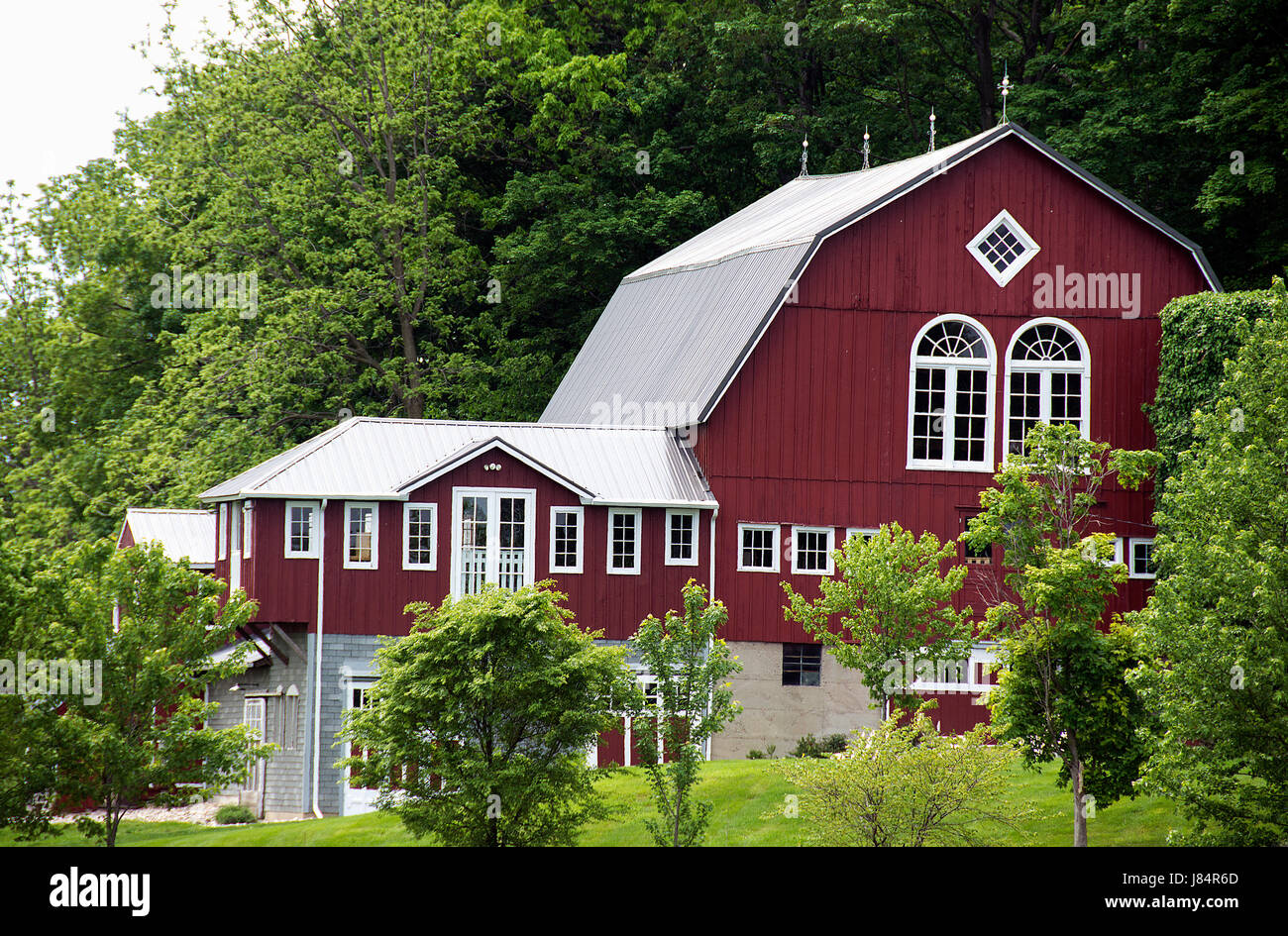 elegant red barn in summer green trees Stock Photo - Alamy