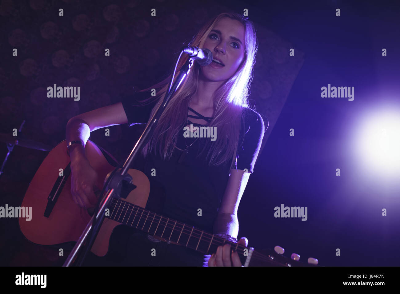 Low angle view of confident female singer performing with guitar in ...