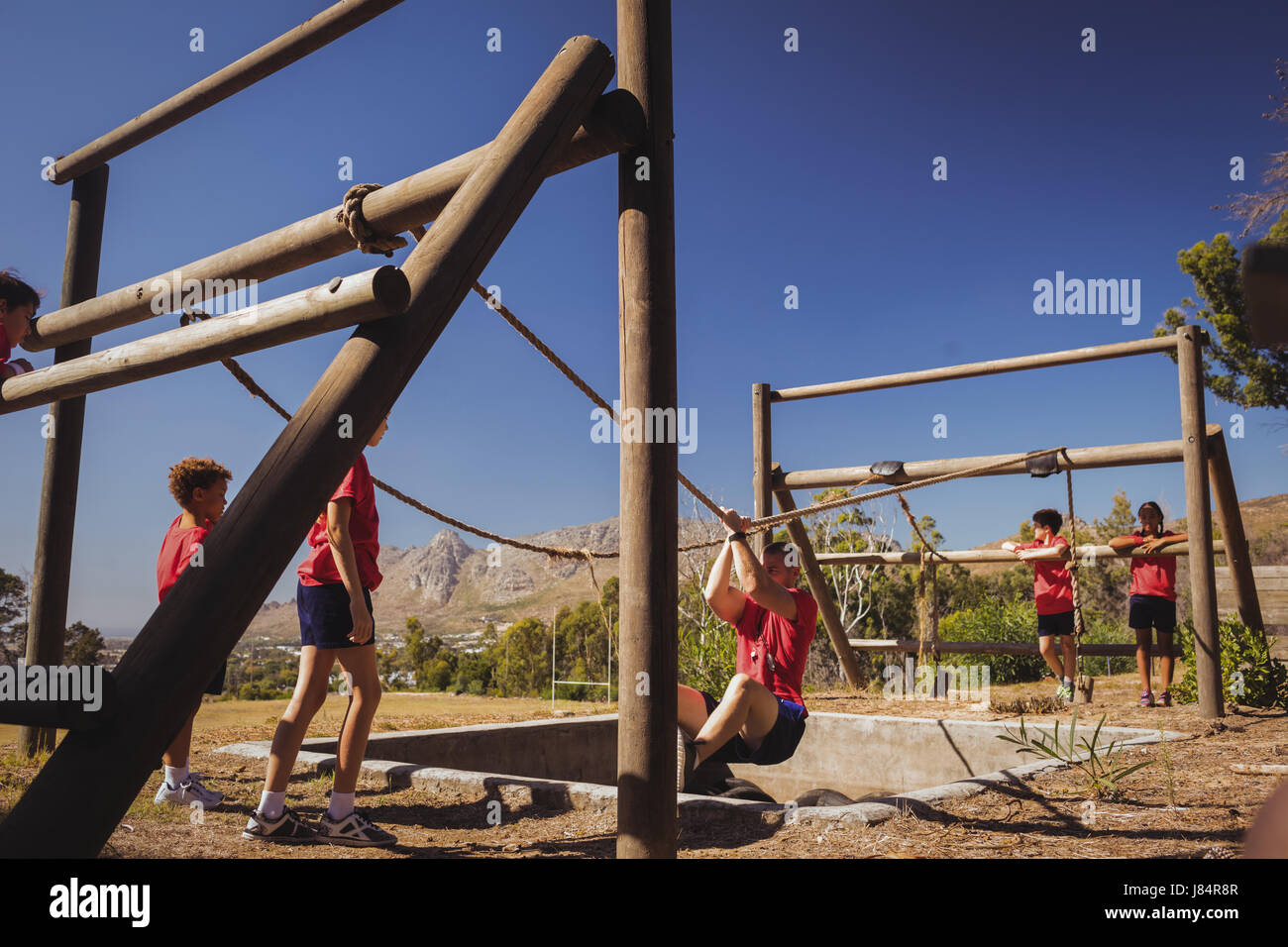 Trainer assisting kids in obstacle course training at boot camp Stock ...
