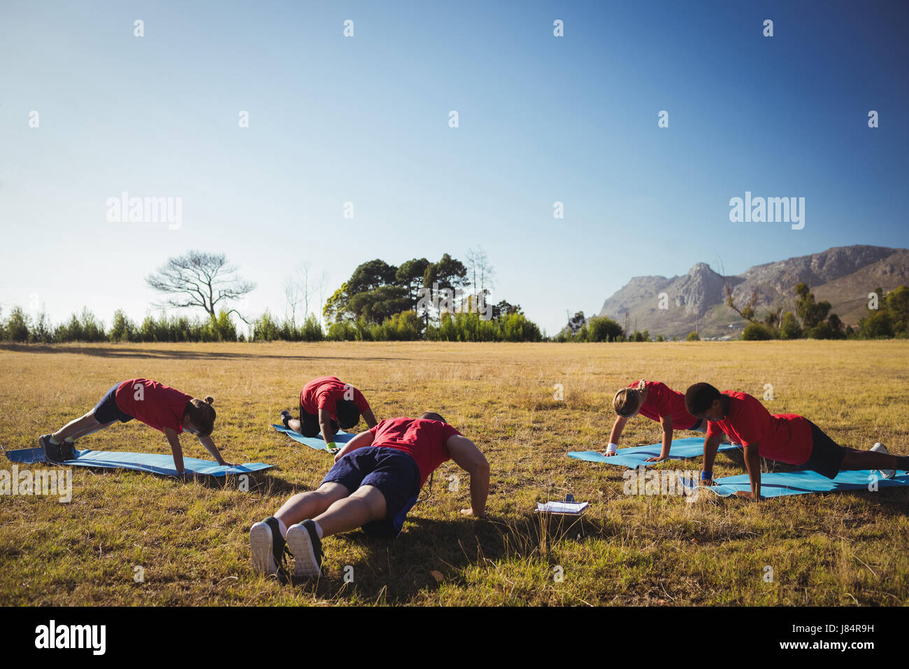 Trainer instructing kids while exercising in the boot camp on a sunny ...