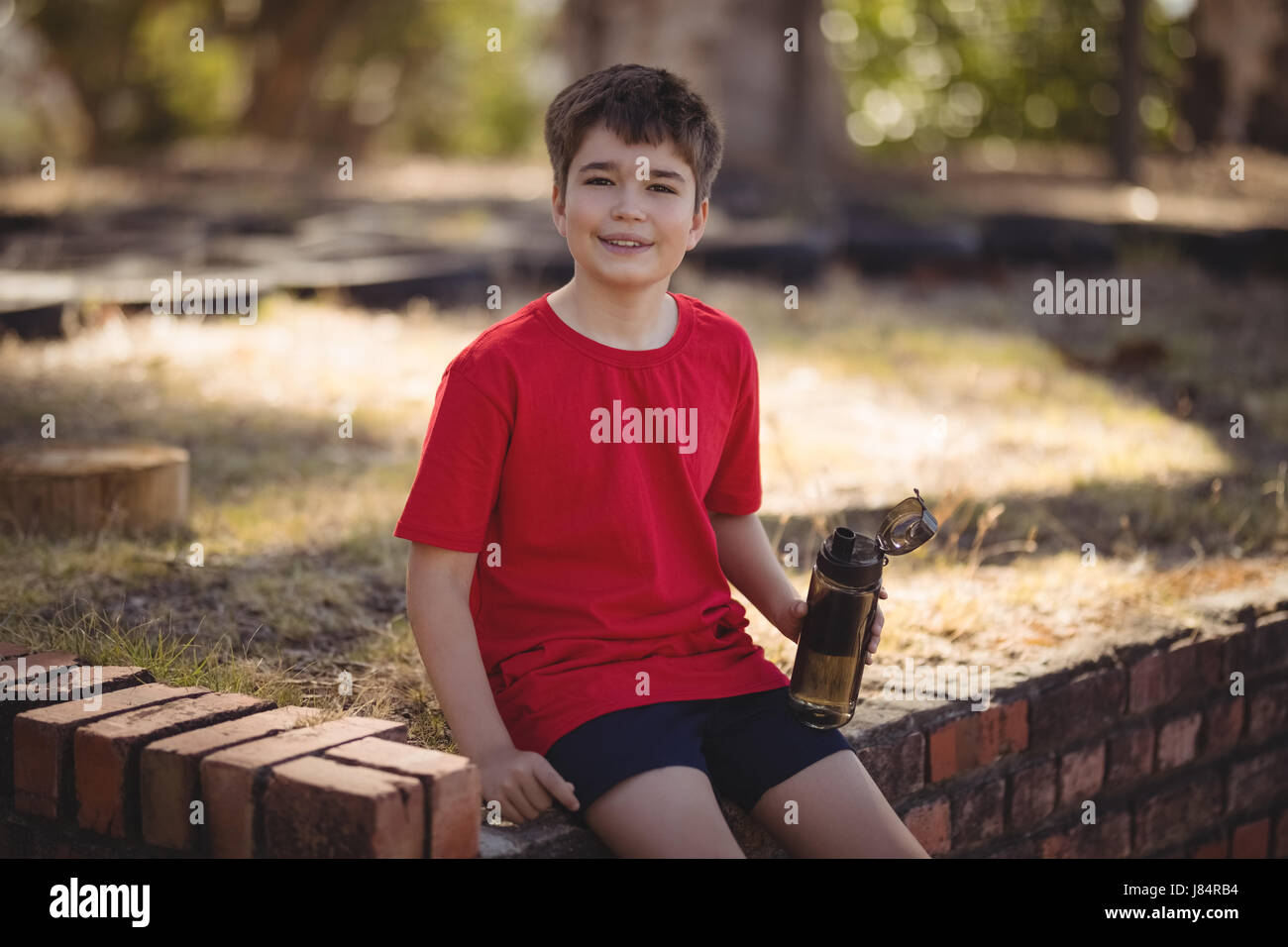 Portrait of happy boy relaxing after workout during obstacle course in ...