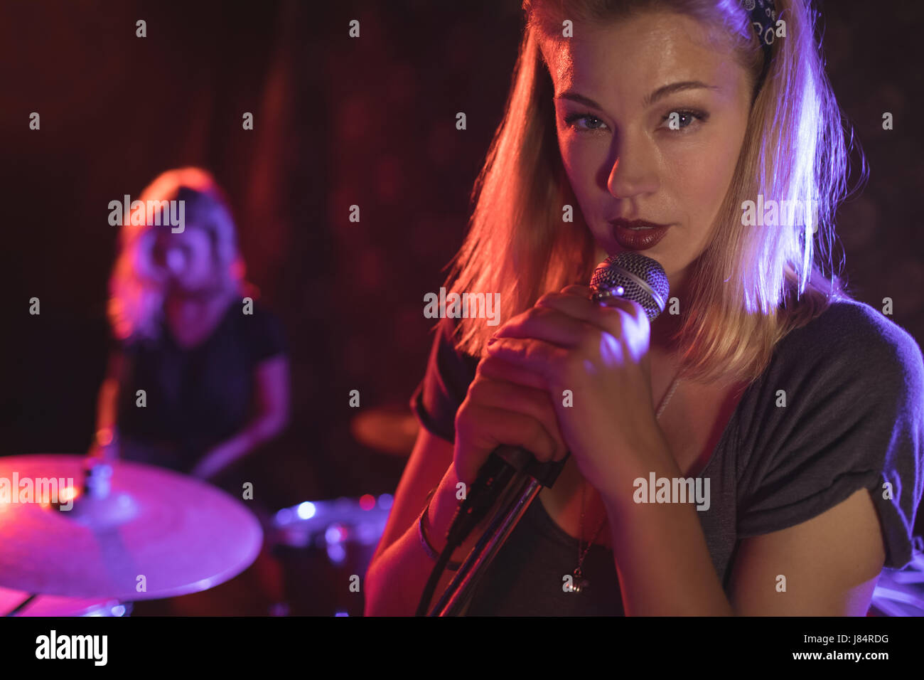 Close up portrait of singer performing with female drummer in nightclub ...