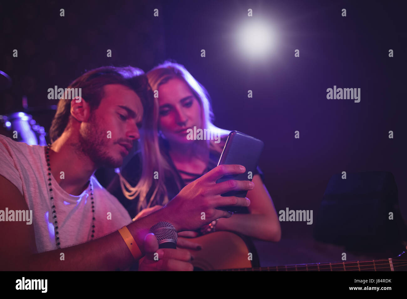 Male and female musicians using mobile phone while practicing in ...