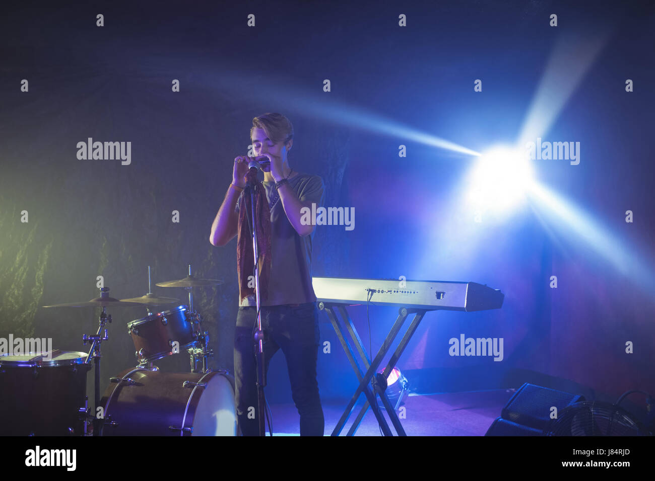 Confident male singer performing on illuminated stage in nightclub ...