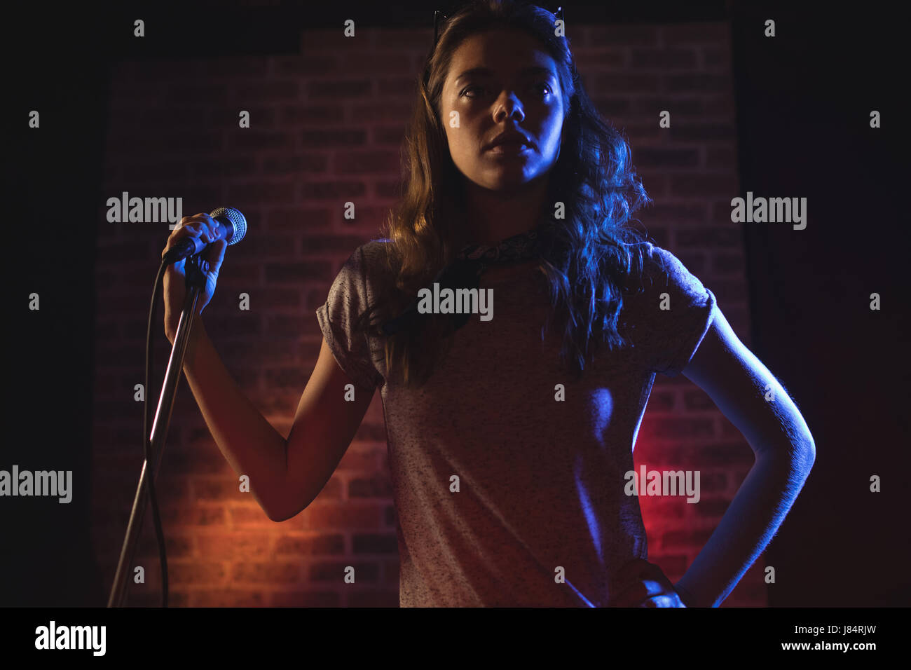 Confident female singer standing against wall in nightclub Stock Photo ...