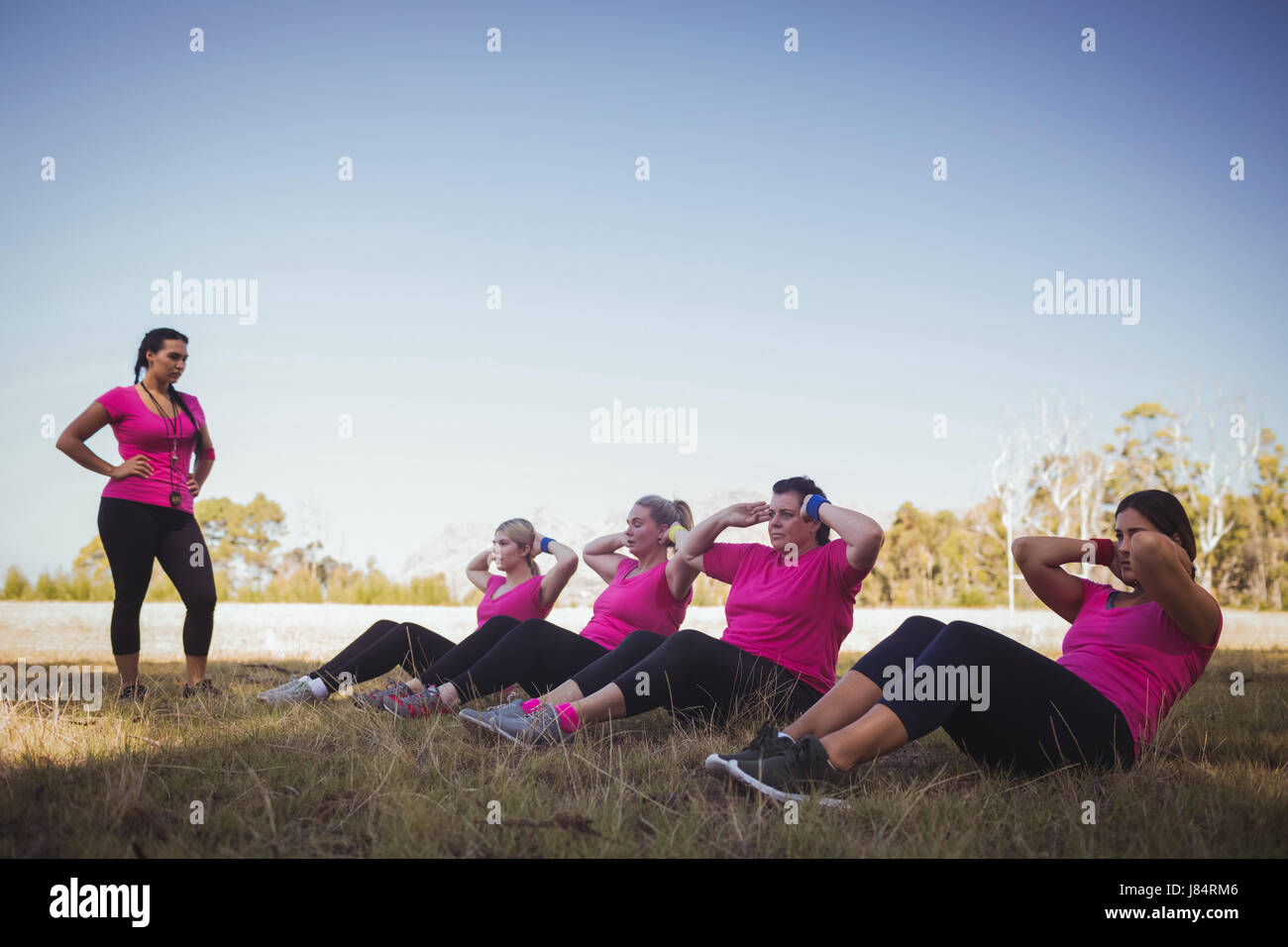 Female trainer instructing women while exercising in the boot camp on a ...