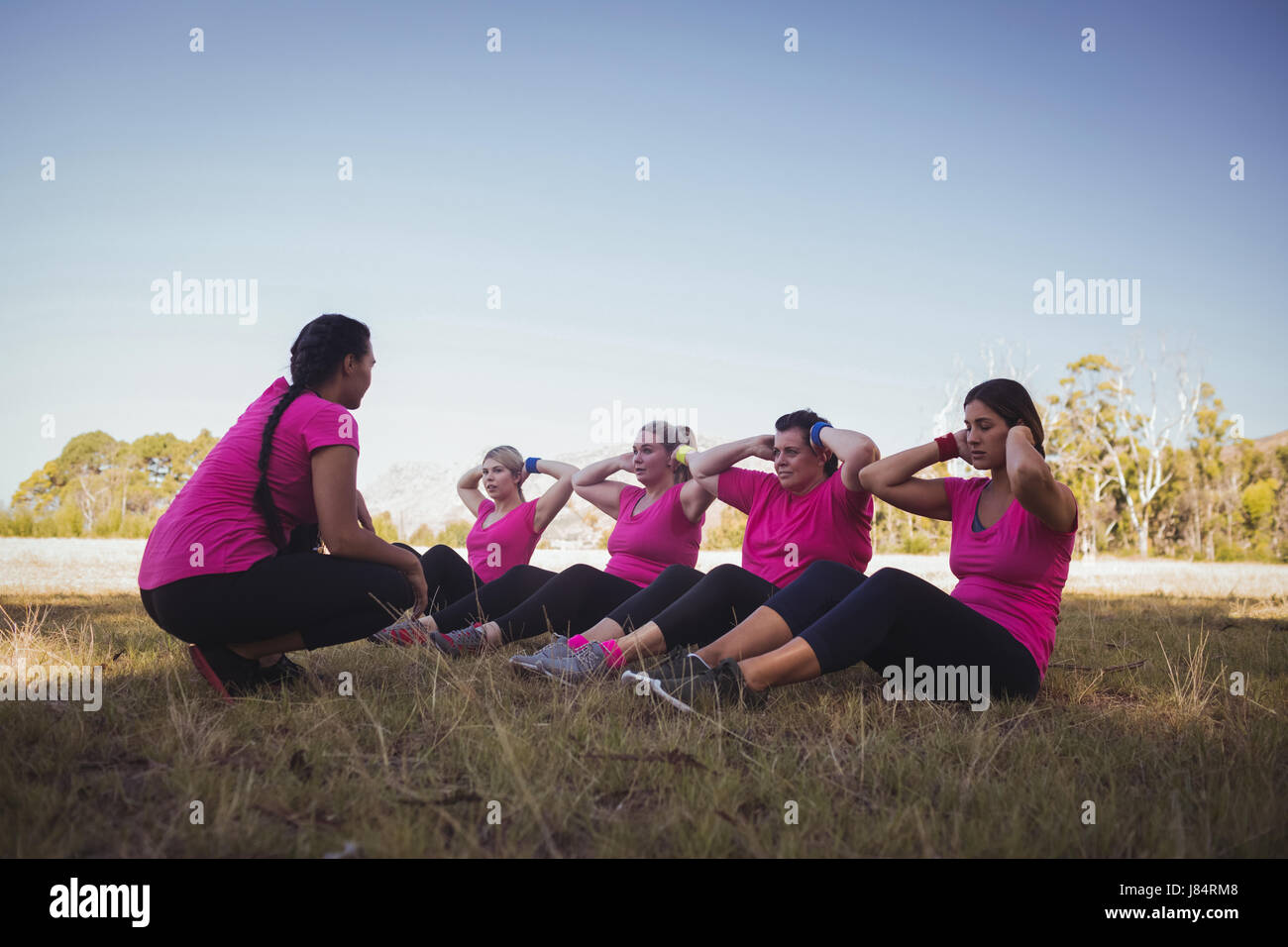 Female trainer instructing women while exercising in the boot camp on a ...