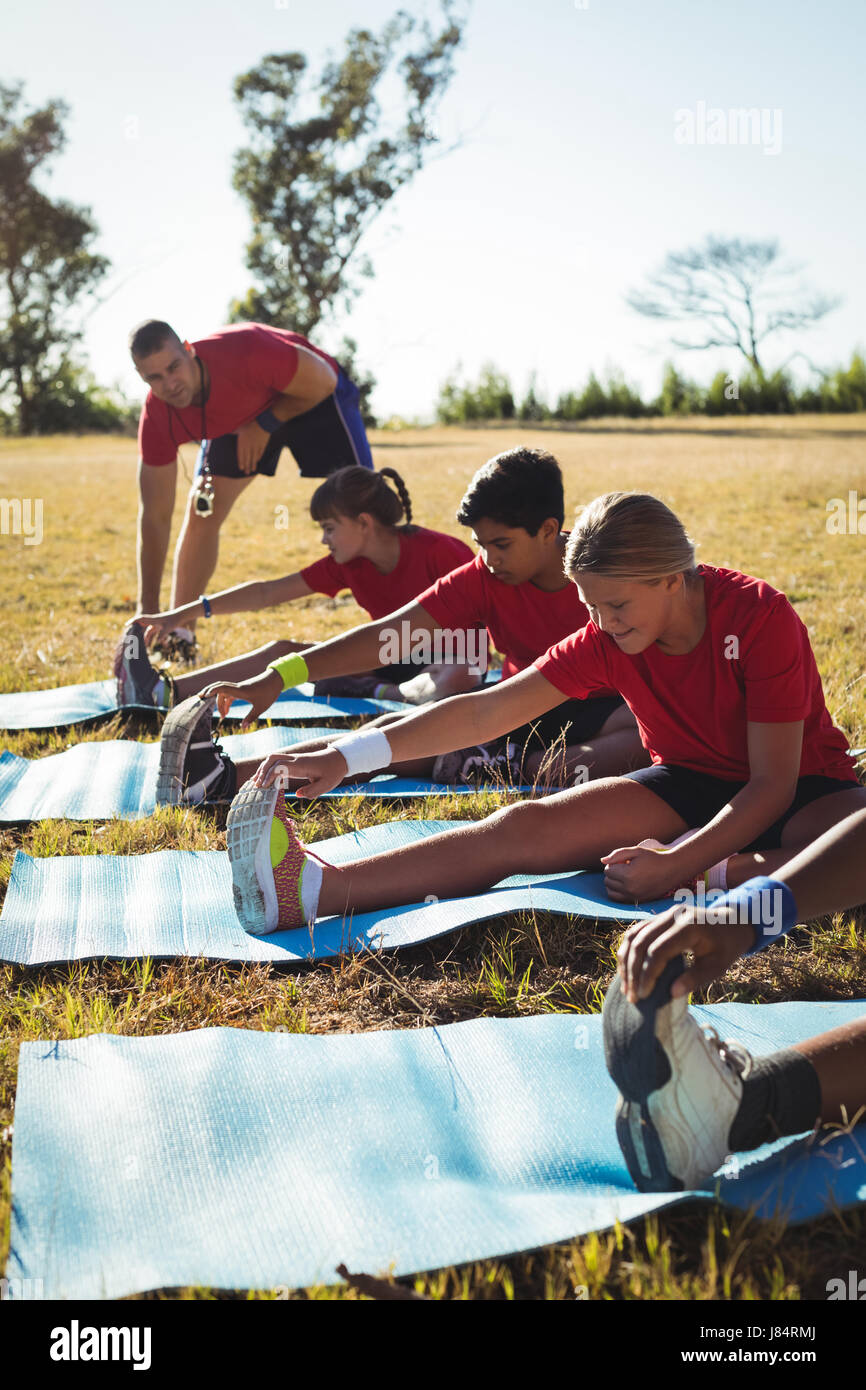 Trainer instructing kids while exercising in the boot camp on a sunny ...