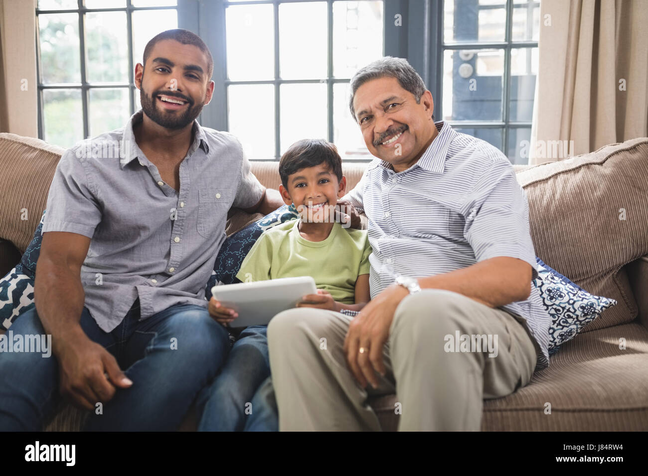Portrait of smiling multi-generation family sitting together on couch ...