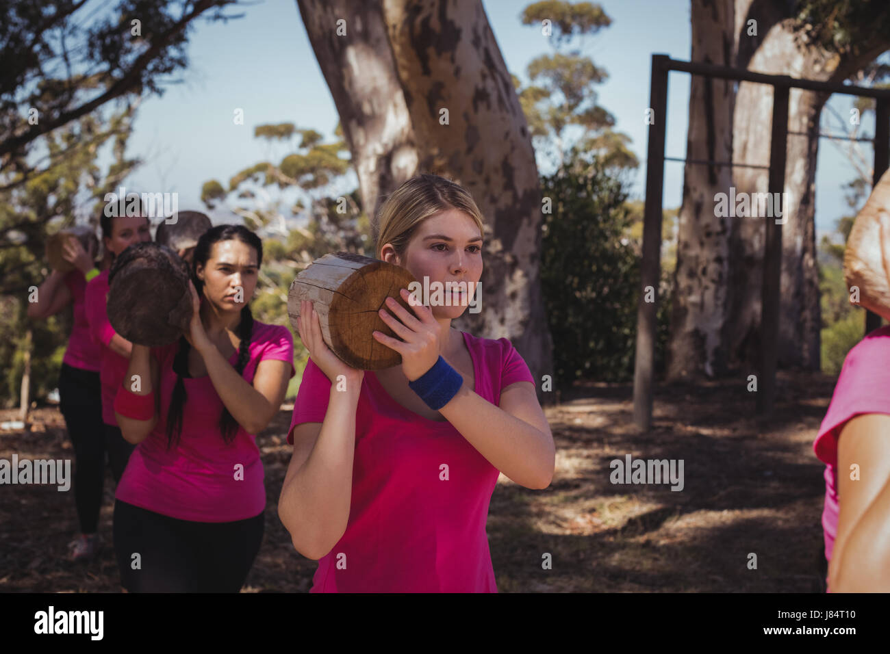 Group of women carrying a heavy wooden log during obstacle course in ...