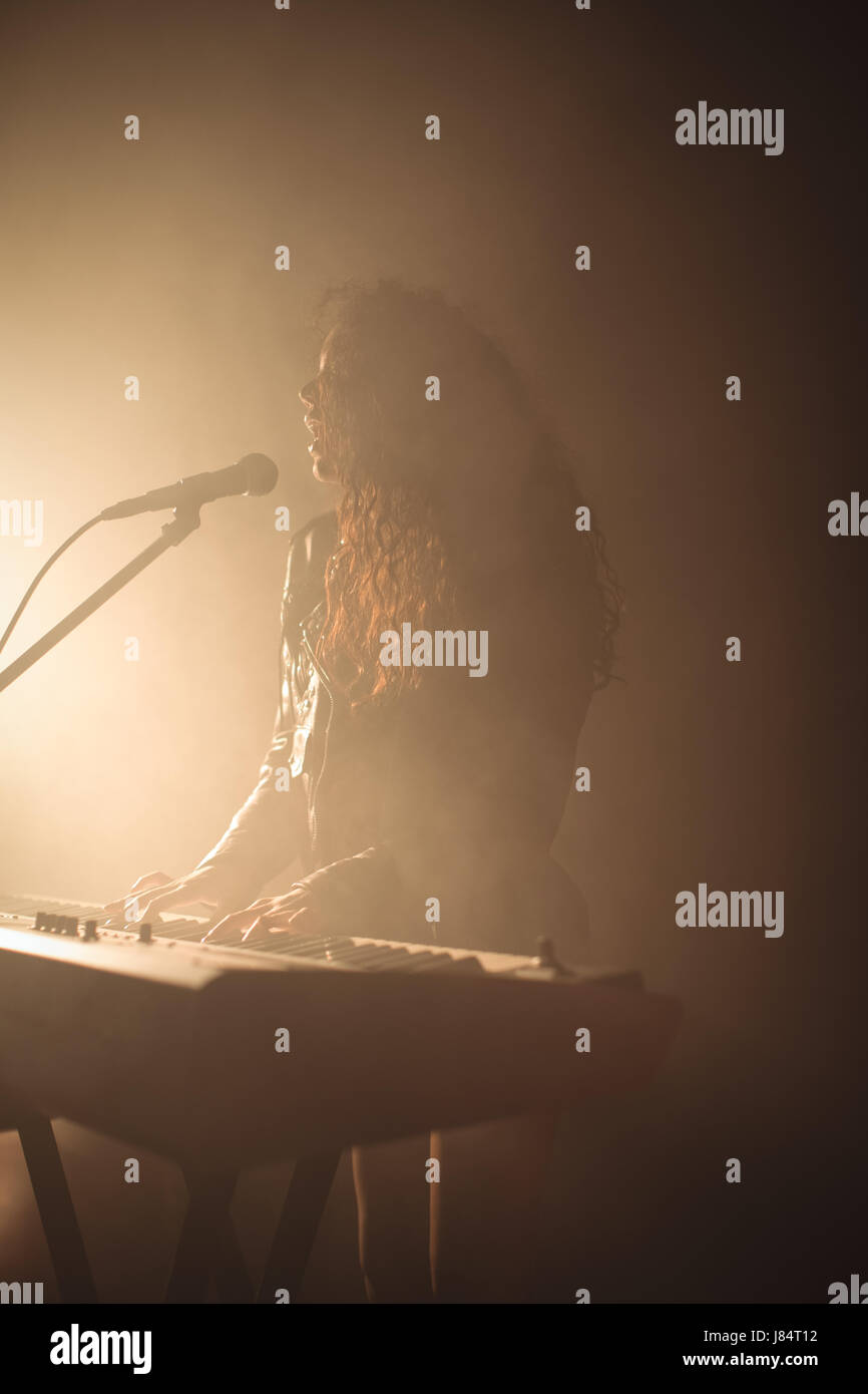 Confident female singer with piano in illuminated nightclub Stock Photo ...