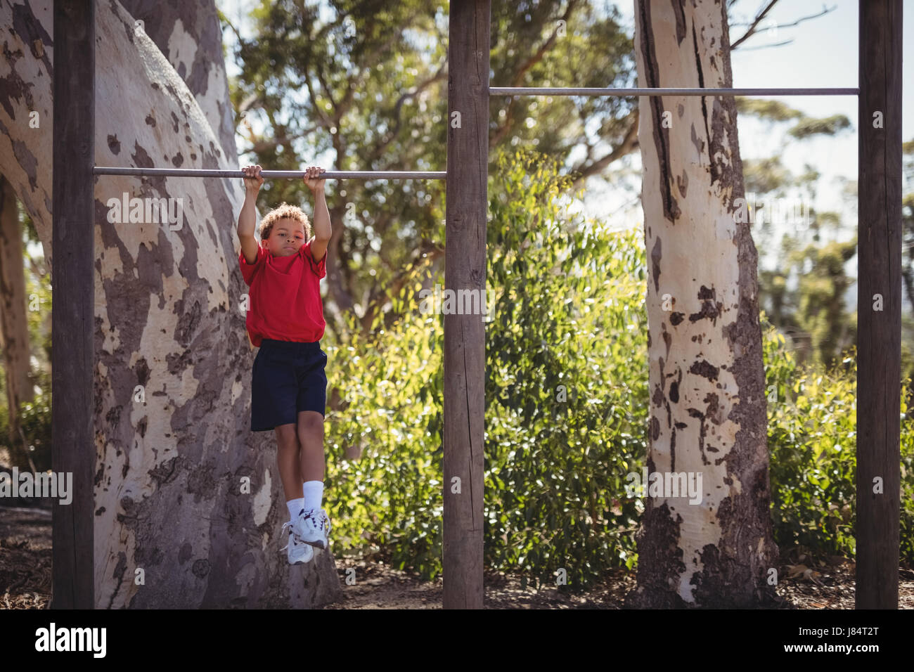 Boy performing pull-ups on bar during obstacle course in boot camp ...