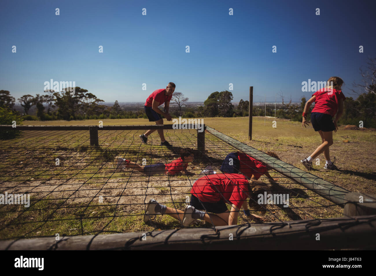 Kids crawling under the net during obstacle course training in the boot ...