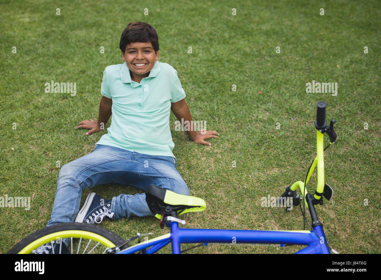 Portrait of smiling boy with fallen bicycle on field at park Stock ...