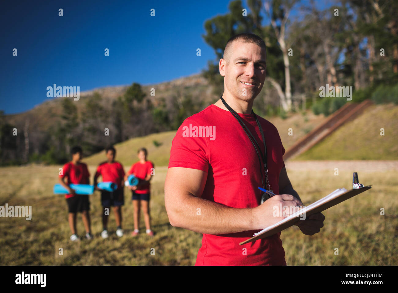 Portrait of trainer writing on clipboard in the boot camp Stock Photo ...
