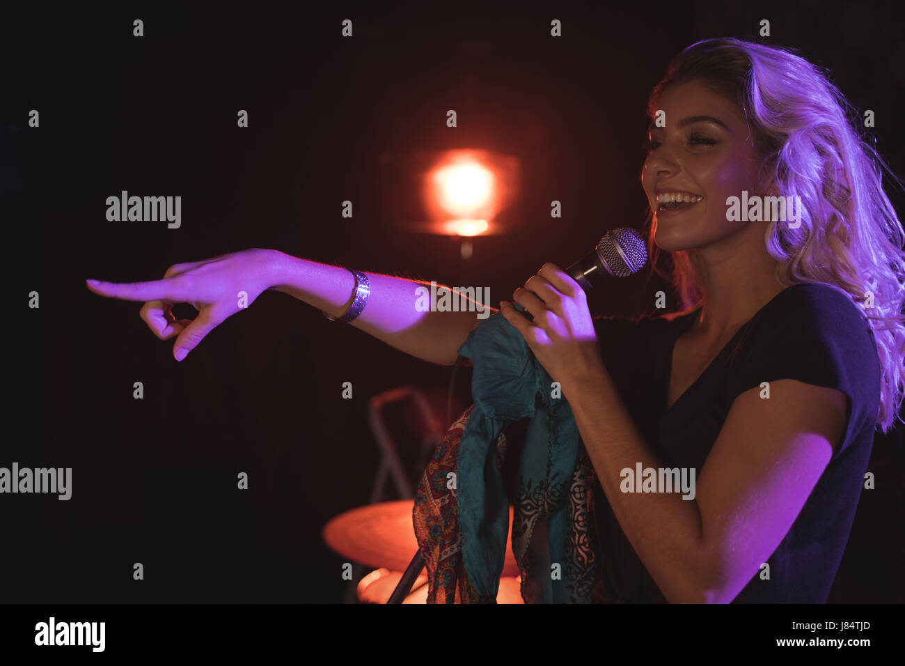 Close up of cheerful female singer pointing while performing in ...