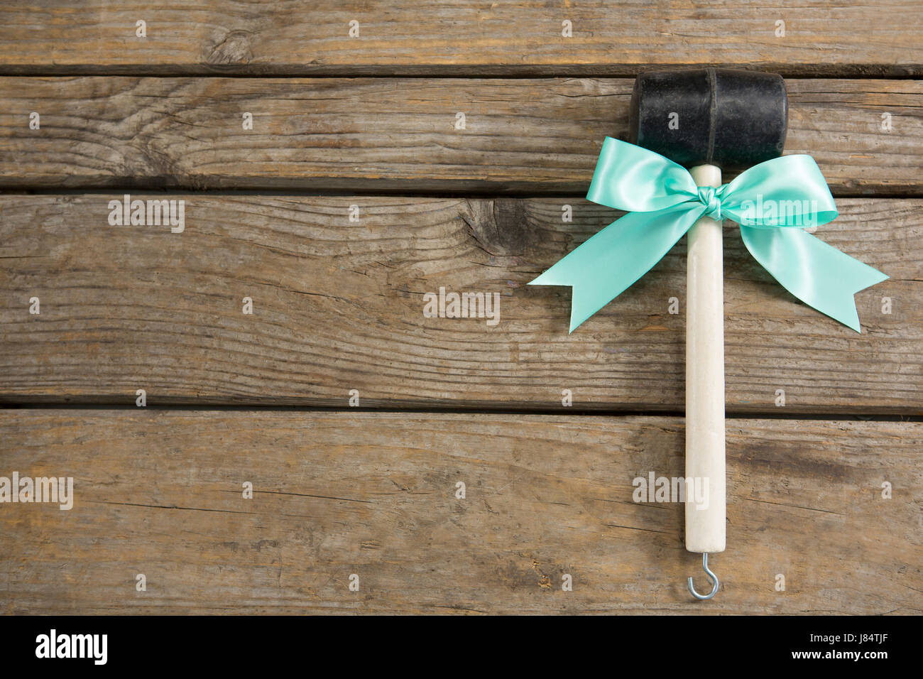 Overhead view of hammer with tied bow on wooden table Stock Photo - Alamy