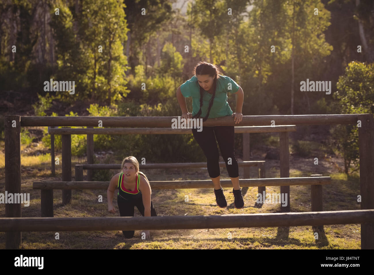 Women exercising on outdoor equipment during obstacle course in boot ...