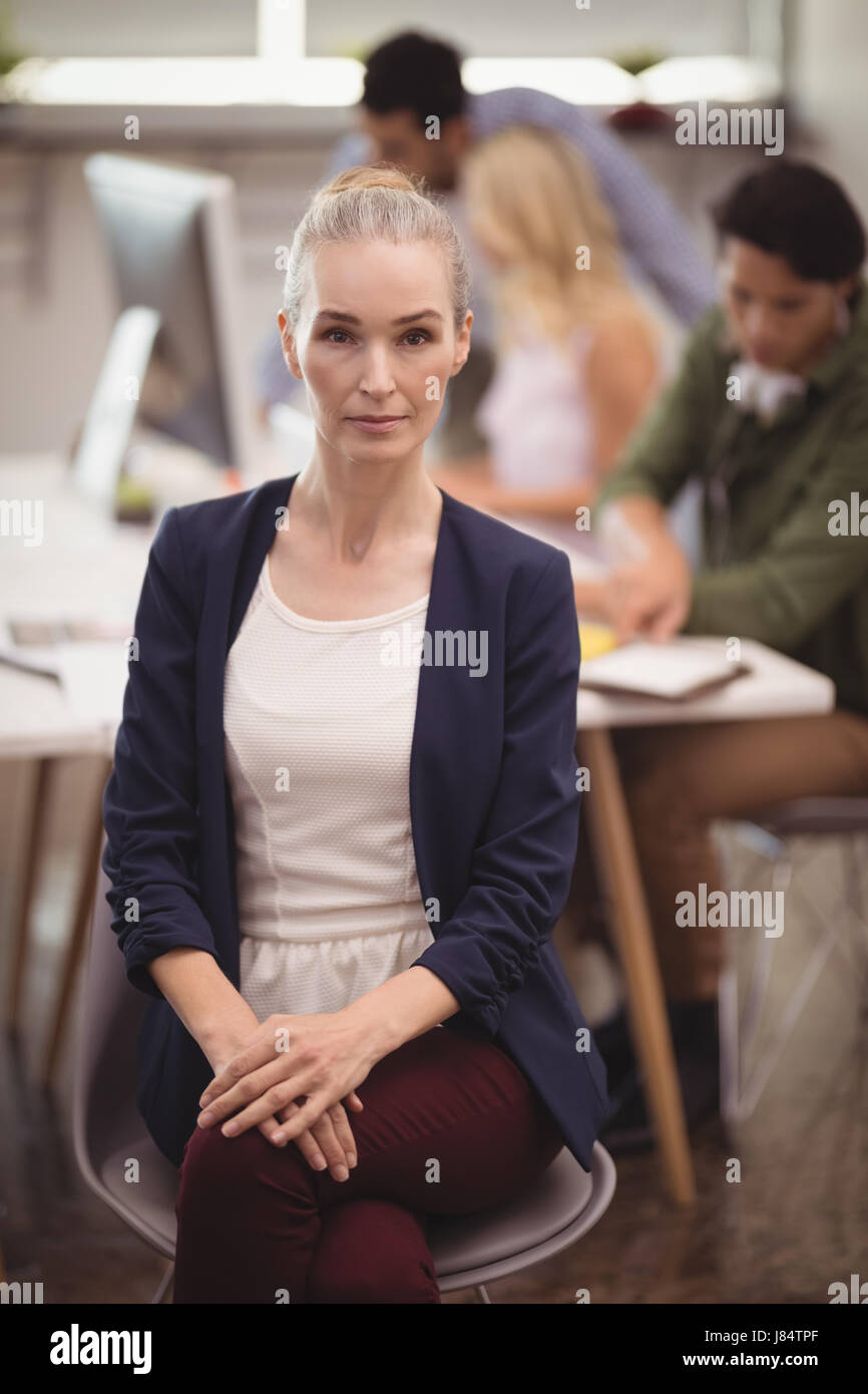 Portrait of serious businesswoman sitting on chair at creative office ...