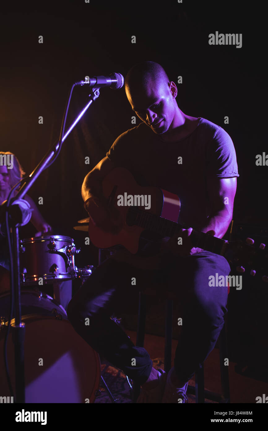 Confident male singer performing with guitar in nightclub Stock Photo ...