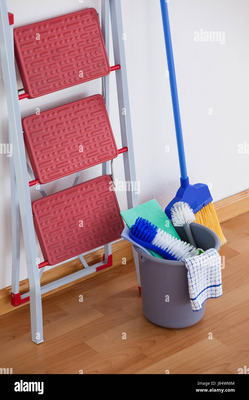 Ladder and cleaning equipment on wooden floor against wall Stock Photo ...