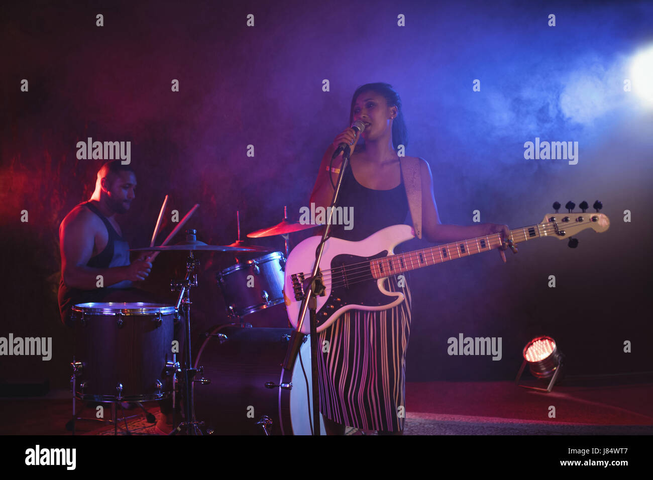 Confident singer and drummer performing in illuminated nightclub Stock ...