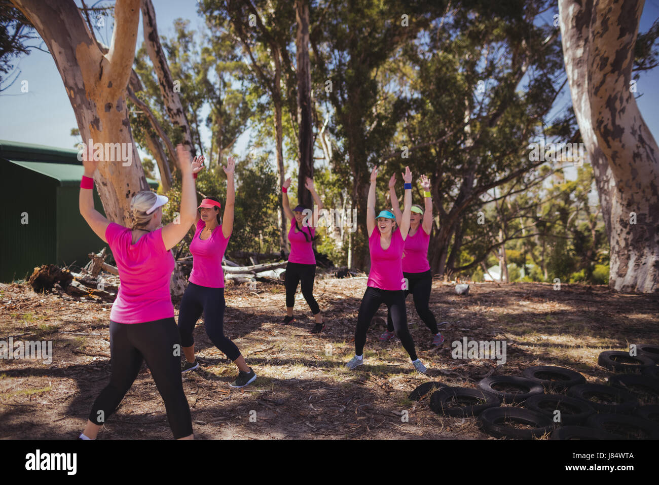 Female trainer instructing women while exercising in the boot camp on a ...