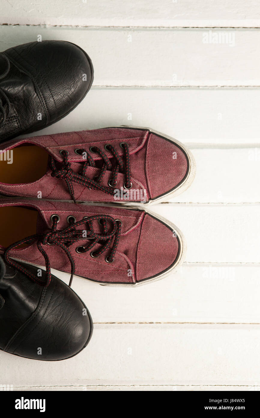 Overhead view of brown loafers and black shoes on white wooden floor ...