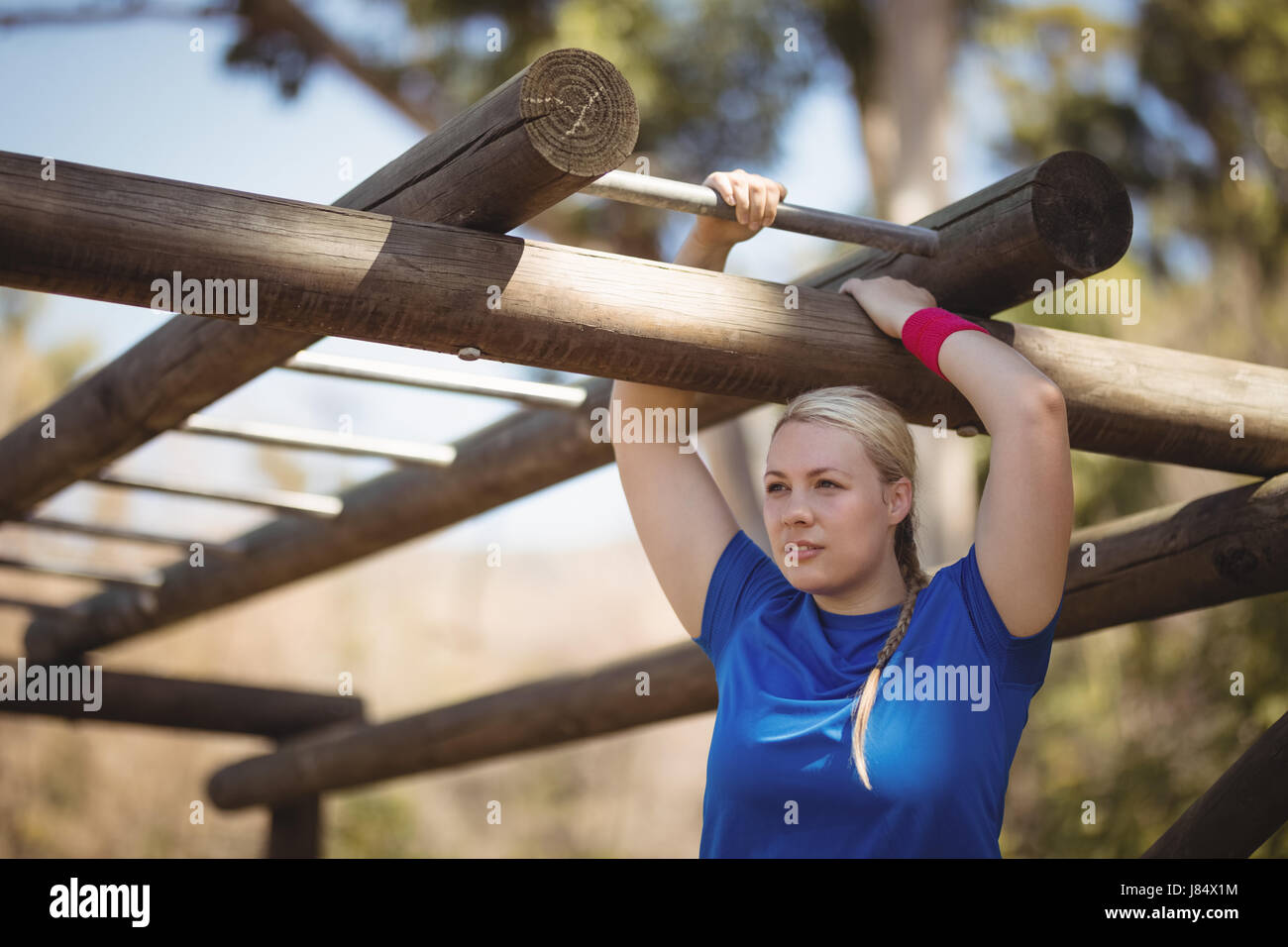 Determined woman exercising on monkey bar during obstacle course in ...