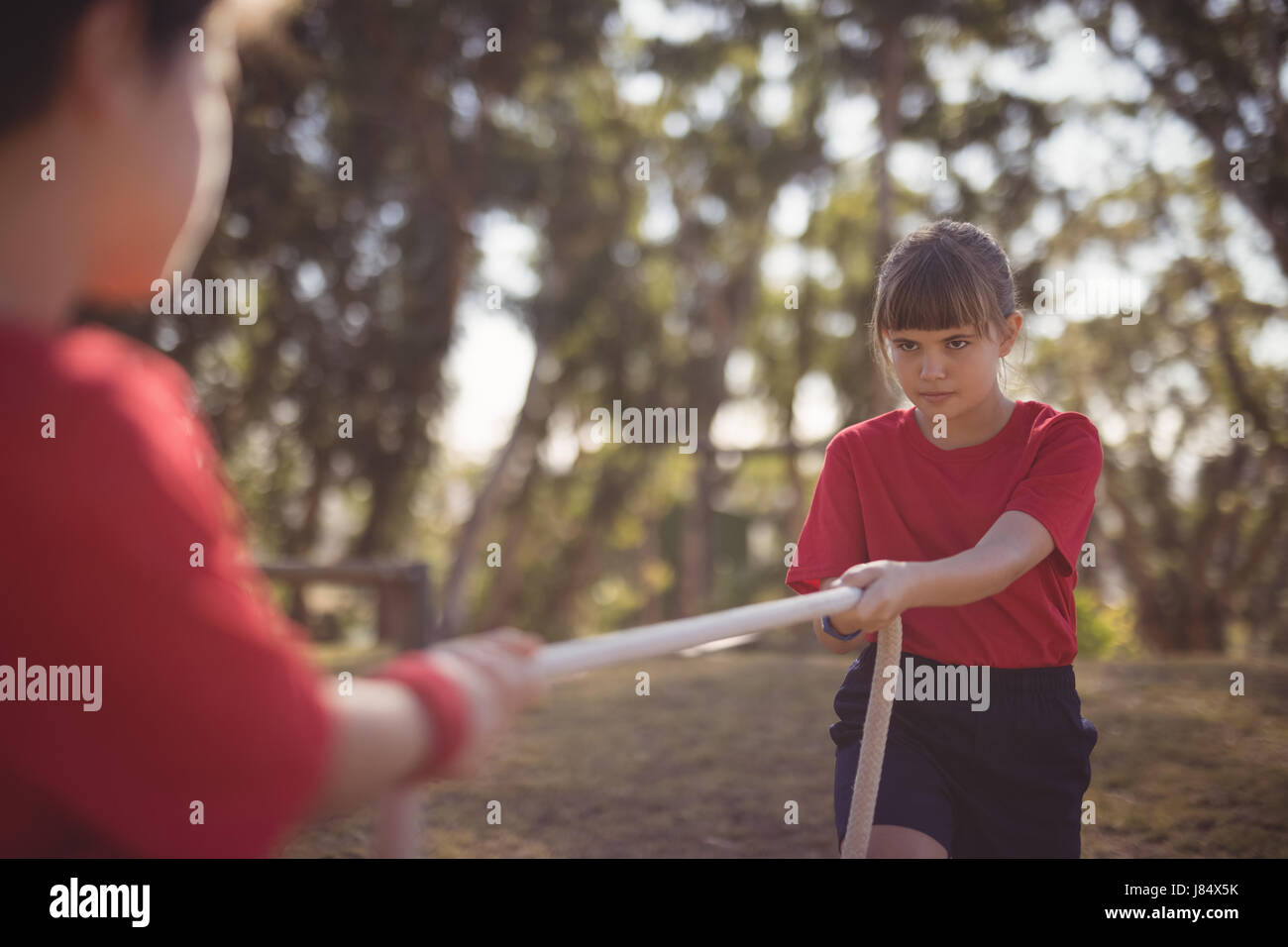 Determined kids practicing tug of war during obstacle course in boot ...
