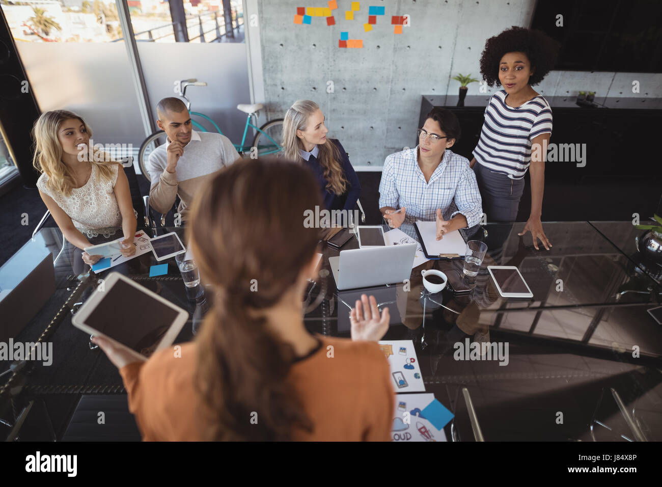 Rear view of businesswoman holding digital tablet while explaining ...