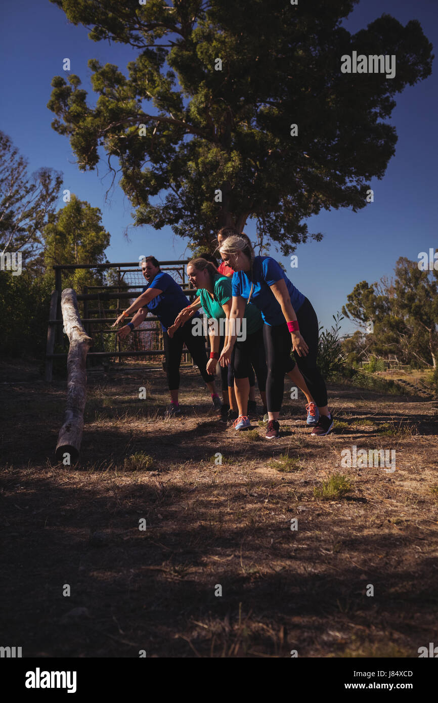 Group of fit women throwing a heavy wooden log during obstacle course ...
