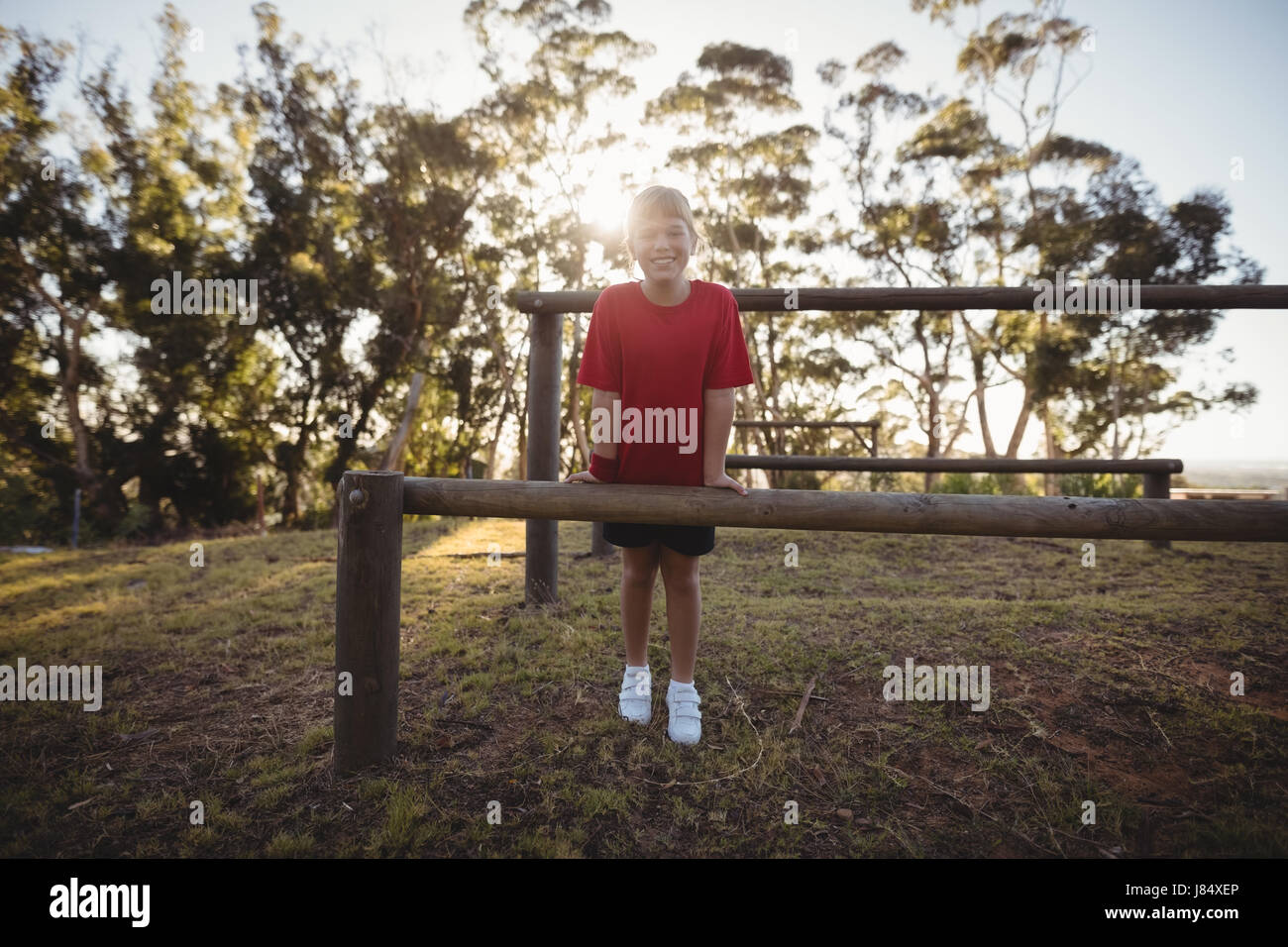 Portrait of happy girl standing near obstacle in boot camp Stock Photo ...