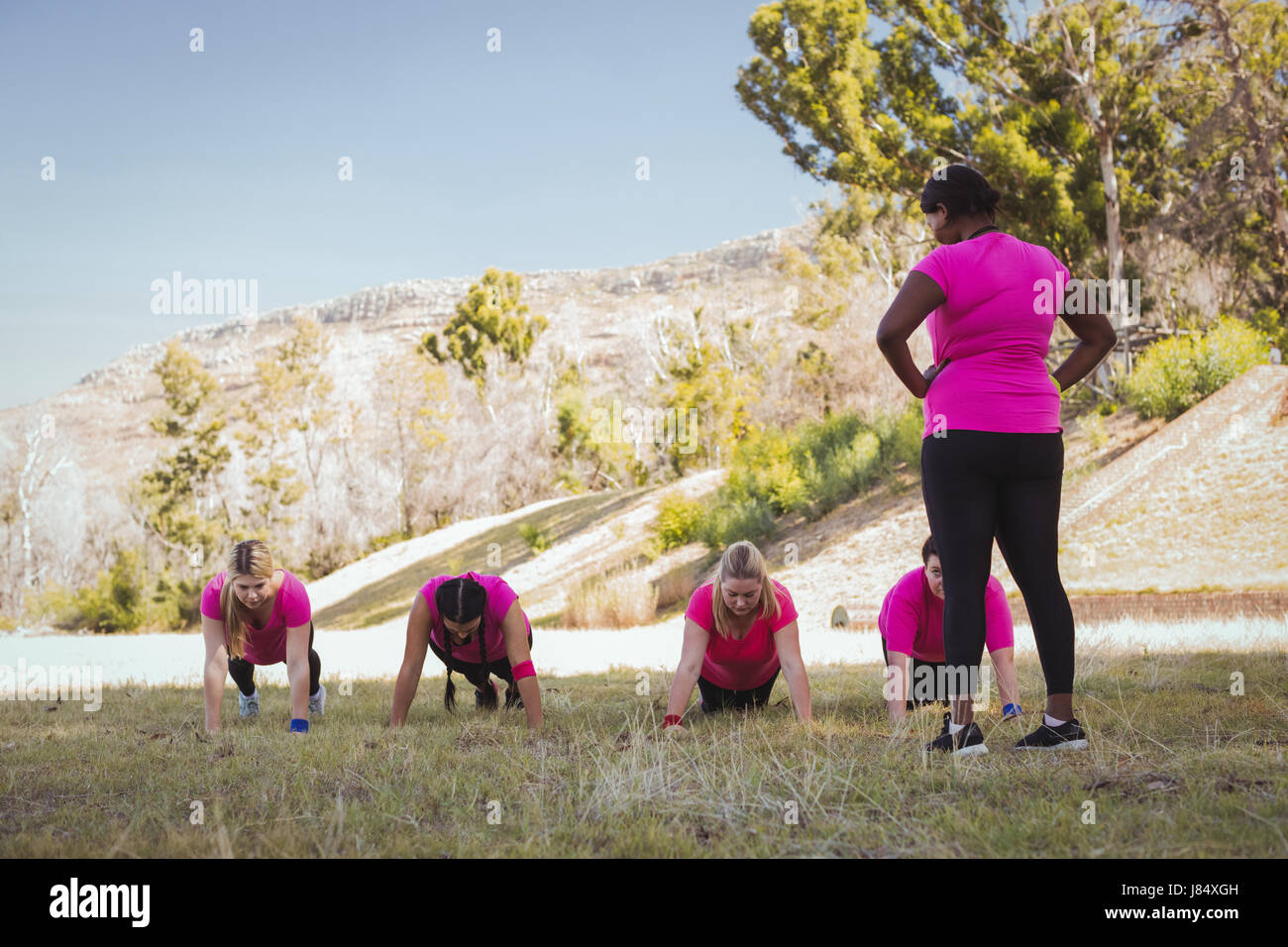 Female trainer instructing women while exercising in the boot camp on a ...