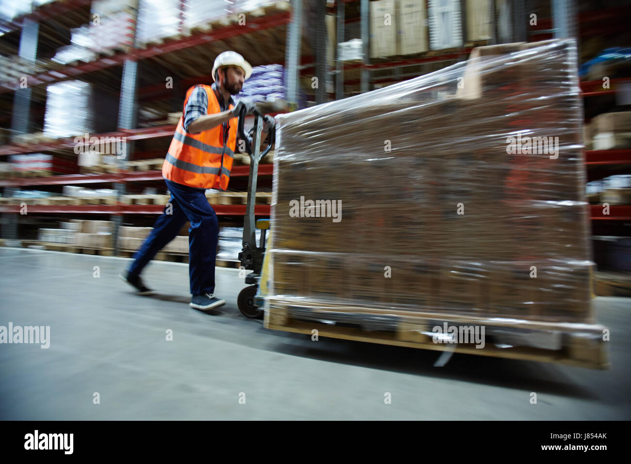 Loader in uniform pushing forklift with packed goods Stock Photo - Alamy