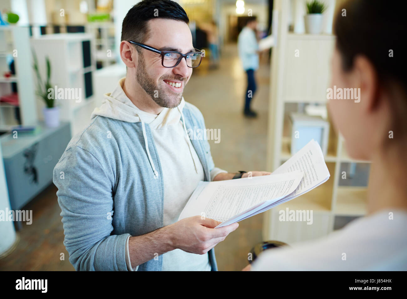 Portrait of handsome modern man discussing documentation with colleague ...
