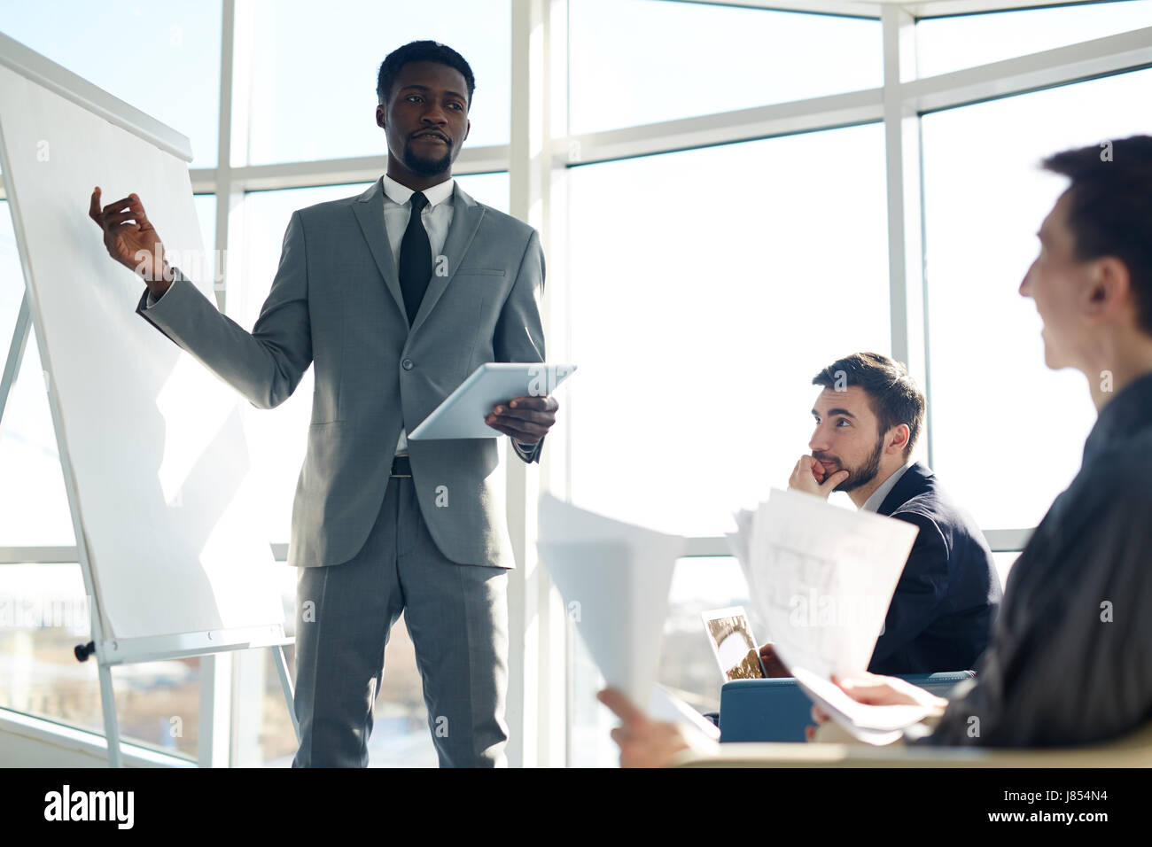Portrait of successful African businessman pointing at whiteboard during presentation meeting ...