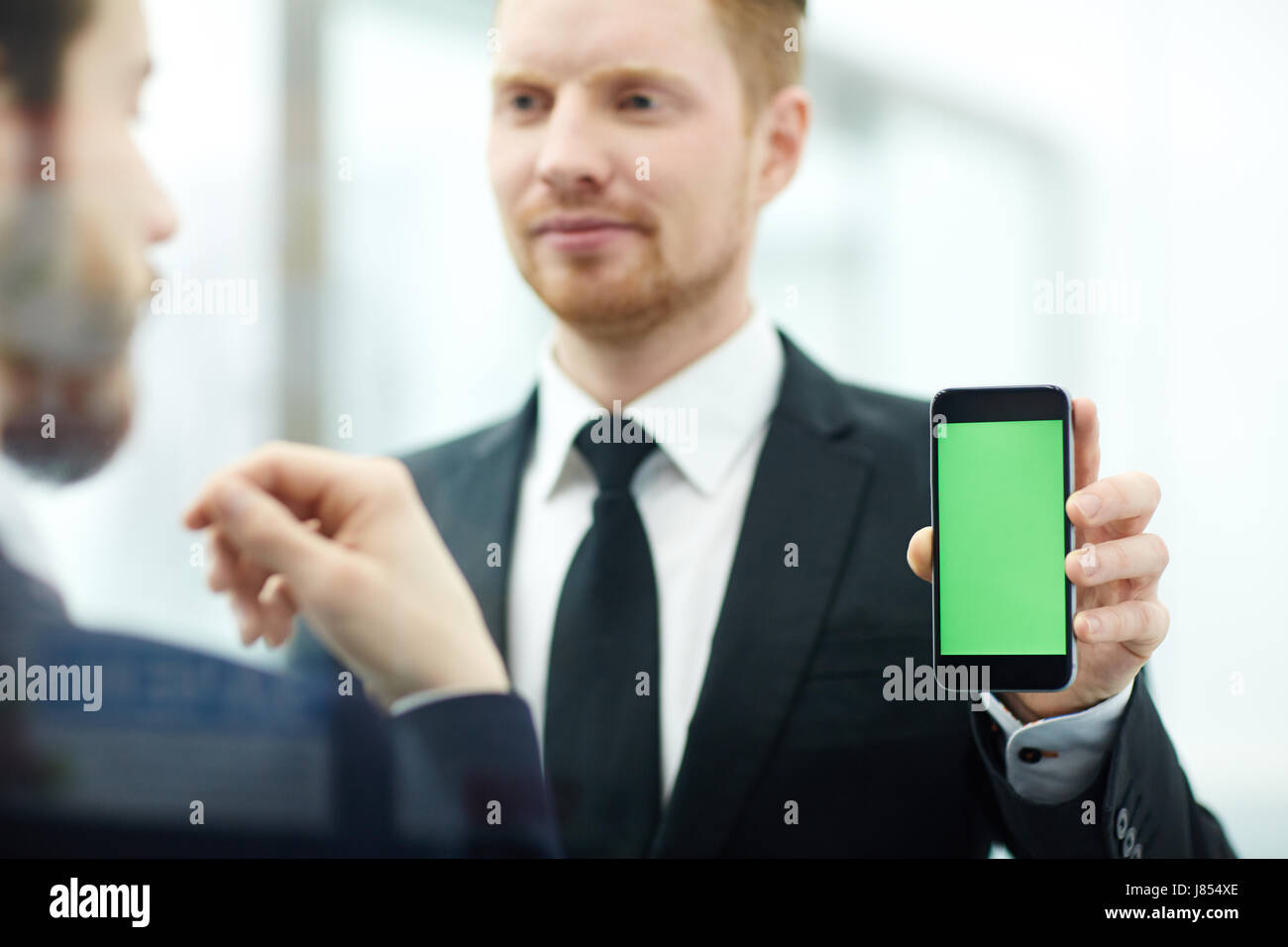 Boss showing something to one of employees in smartphone Stock Photo ...