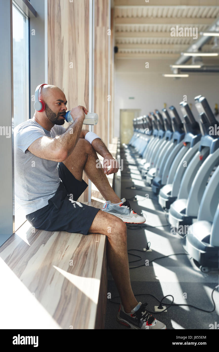 Thirsty man drinking water in gym after training Stock Photo - Alamy