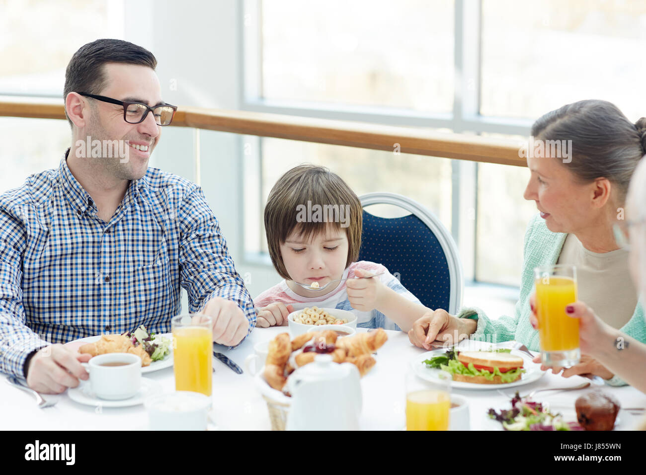 Aged woman, young man and little boy having dinner in cafe Stock Photo ...