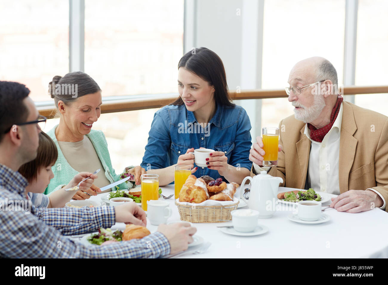 Big family sitting by table and having dinner Stock Photo - Alamy