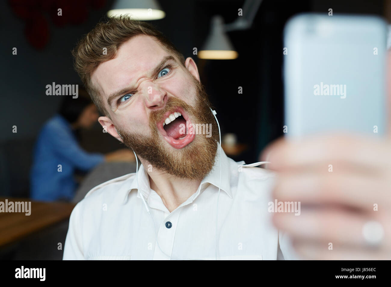 Portrait of modern bearded man yelling and grimacing angrily to camera ...